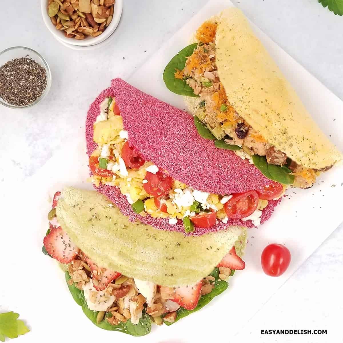 Three colorful Brazilian tapioca crepes with fillings.